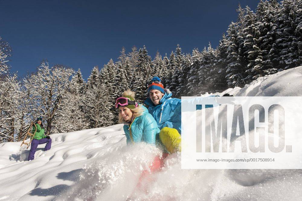 Austria, Salzburg, Young man and women with sledge in snow at ...