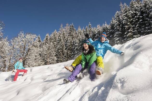 Austria, Salzburg, Young man and women with sledge in snow at ...
