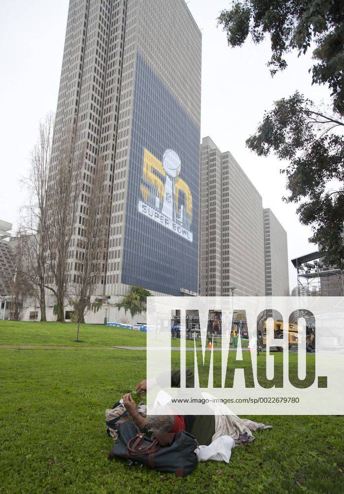 A homeless man sleeps rough in the rain at a Super Bowl 50 fan area ...