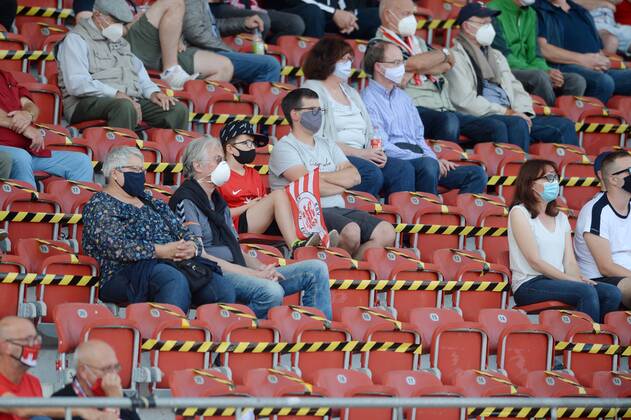 Spectators with mask and distance on the tribune, corner flag, logo ...