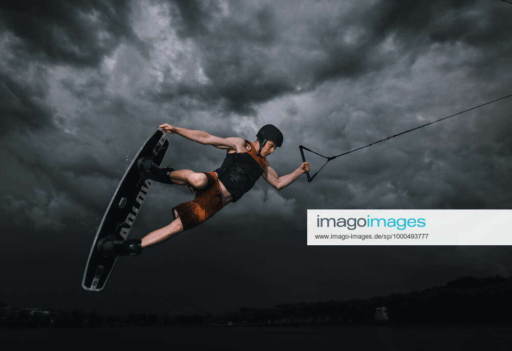 Dramatic picture of man wakeboarder athlete jumping while performing ...