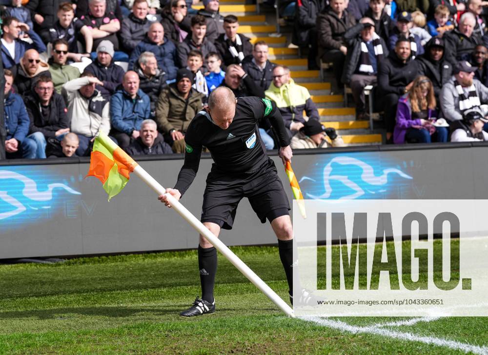 Assistant Referee David Roome replaces a corner flag blown out of its ...
