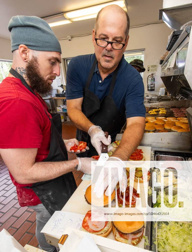 Syndication: Ocala StarBanner Jon McMillan places a hamburger patty ...