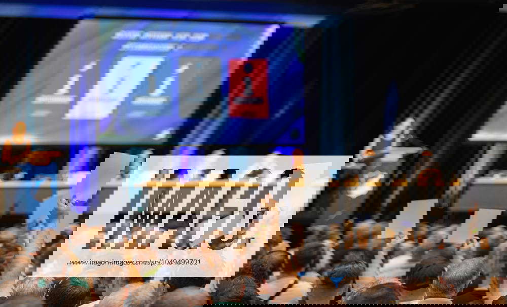 In the picture Several members raise their voting cards in the air ...