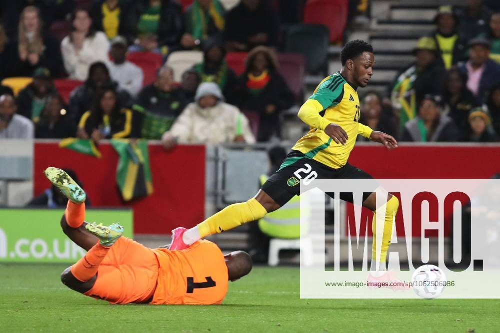 Renaldo Cephas of Jamaica is fouled by Trinidad and Tobago goalkeeper ...