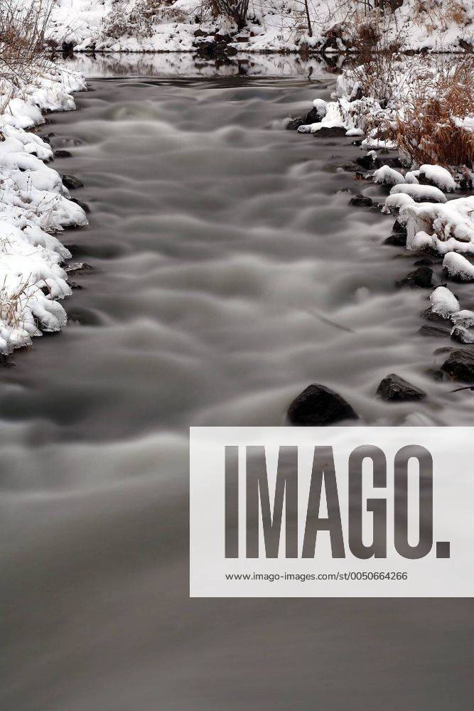 Der Fluss Ilm in Thüringen mit verschneiten Ufern wirkt durch ...