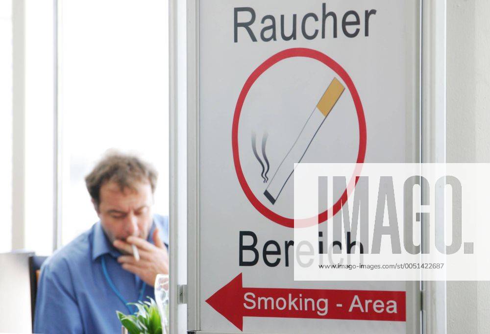 Raucher hinter einem Hinweisschild für den Raucherbereich auf dem ...