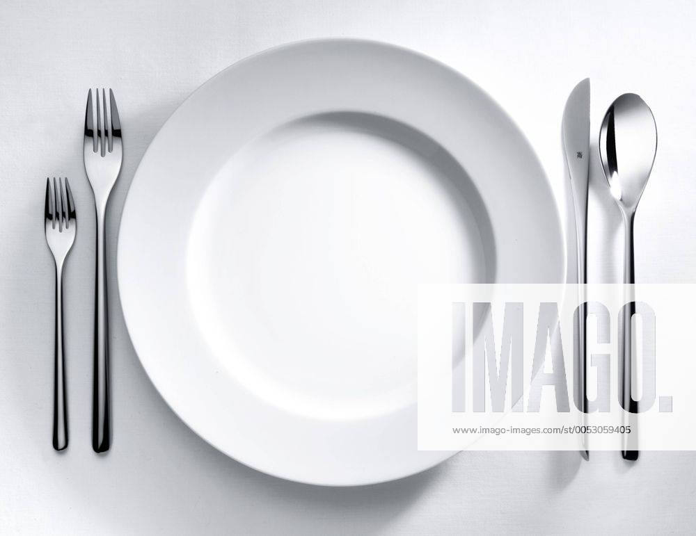 Teller mit Besteck auf weißer Tischdecke