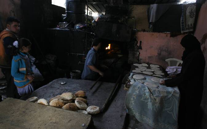 A Palestinian baker prepares bread in a wood burning stove at a ...