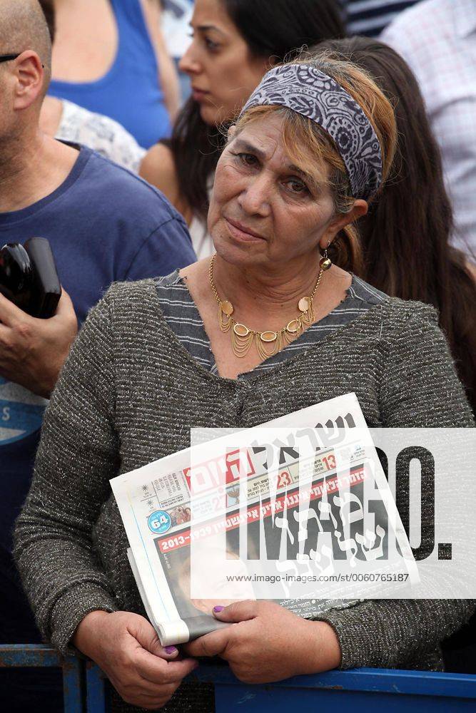 An Israeli woman holds the newspaper reporting the death of late ...