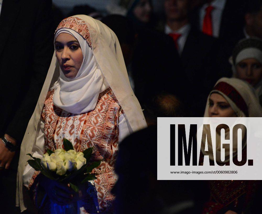 A Palestinian bride holds flowers during a mass wedding of 250 couples ...