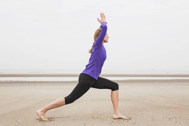 Woman stretching leg lying down on exercise mat at beach model released ...