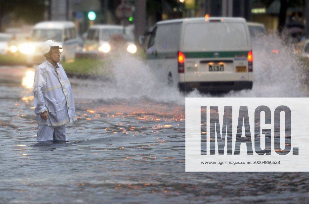 NAGOYA, Japan - A police officer directs traffic on a flooded road ...