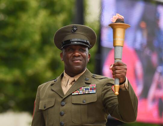 Sergeant Major Ronald Green, USMC, holds the torch during opening ...