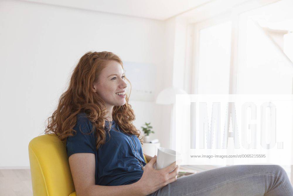 Happy Young Woman With Cup Of Coffee Sitting In Her Living Room Model