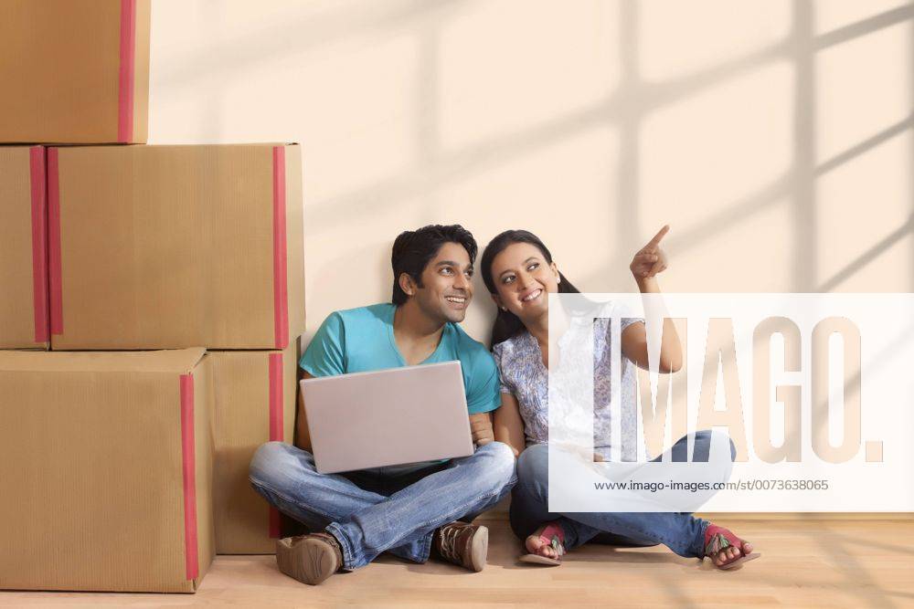 Young couple online shopping and pointing with finger to show something at new home