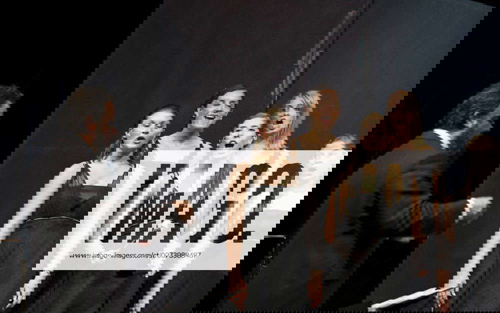 The conductor leads as his choir of teenage girls sings. One girl plays ...