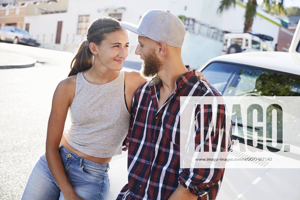 Young couple in love sitting on car bonnet model released Symbolfoto