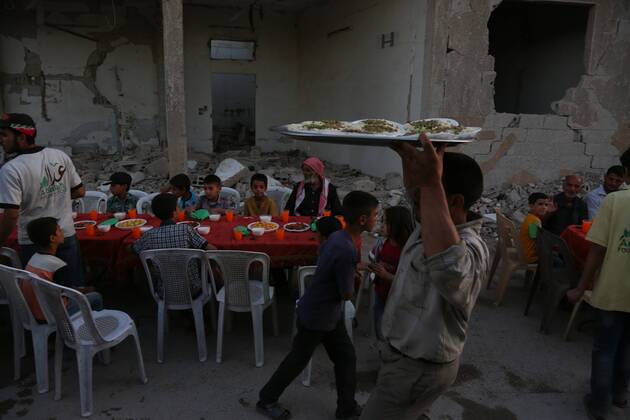 Douma, Damascus, Syria - A man carries plates with food in preparation ...