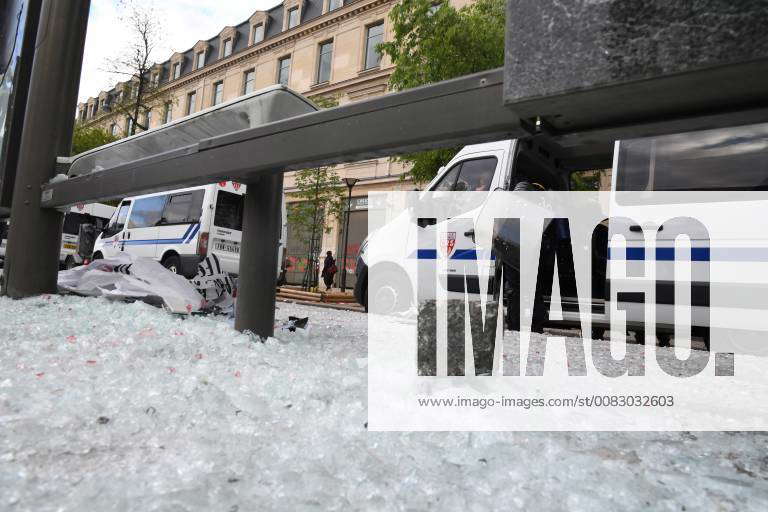 Riot police stand in front of a damaged bus stop after clashs broke out ...