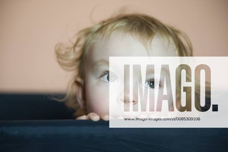 Baby girl peering over side of crib, portrait