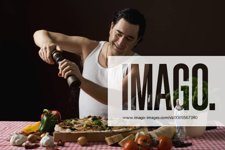 Stereotypical Italian man using a pepper mill on his pizza