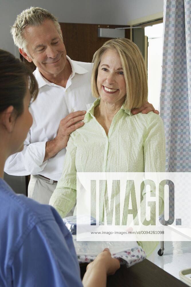 Nurse giving examination gown to female patient,model released, Symbolfoto