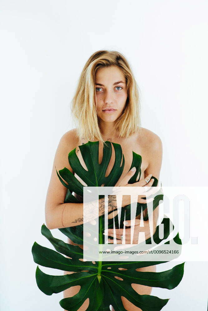 Young naked woman covering her body palm leaf on white background ...