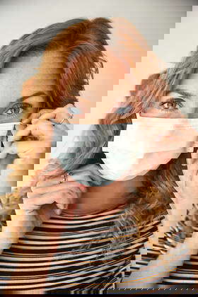 Portrait of red-haired woman wearing a face mask at home model released ...