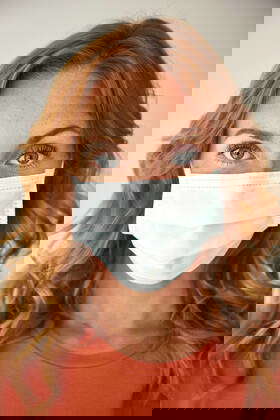 Portrait of red-haired woman wearing a face mask at home model released ...