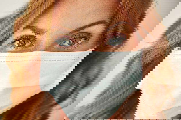 Portrait of red-haired woman wearing a face mask at home model released ...