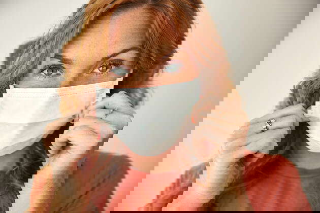 Portrait of red-haired woman wearing a face mask at home model released ...