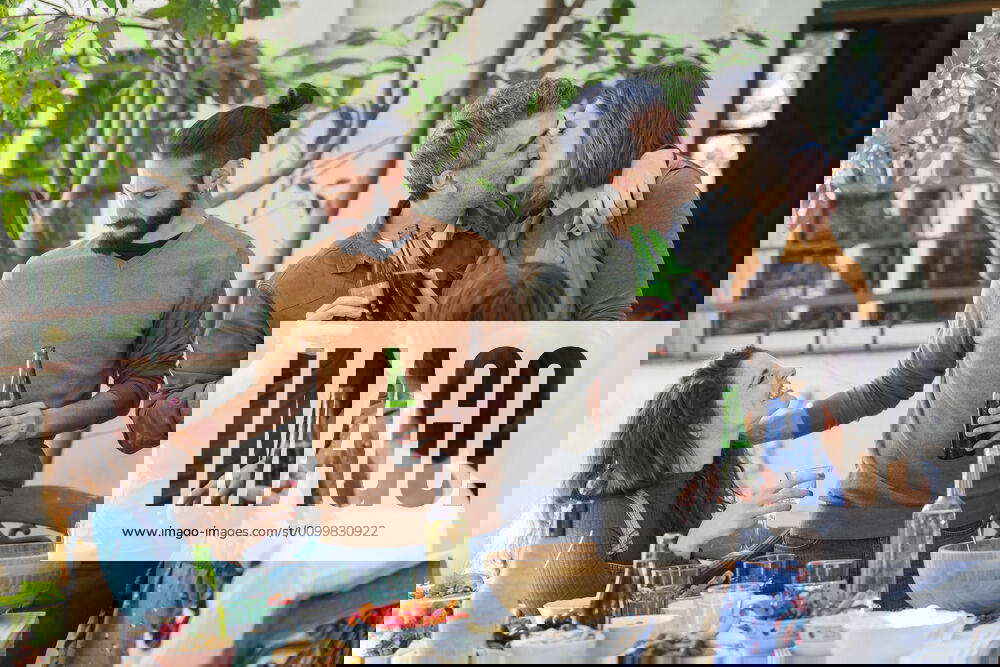 Happy friends enjoying lunch in the countryside, drinking wine and beer ...