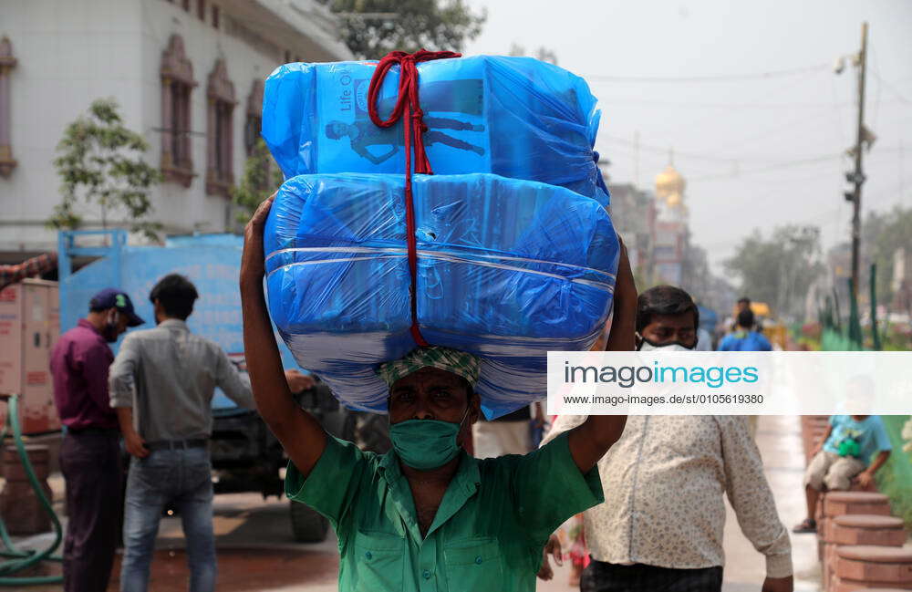 New Delhi, India: A man wearing a face mask carries goods during the ...