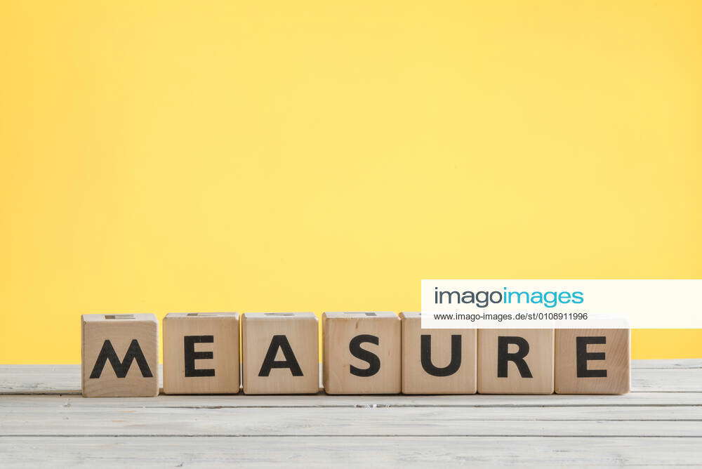 Measure sign on a yellow background Measure sign with wooden cubes on a ...