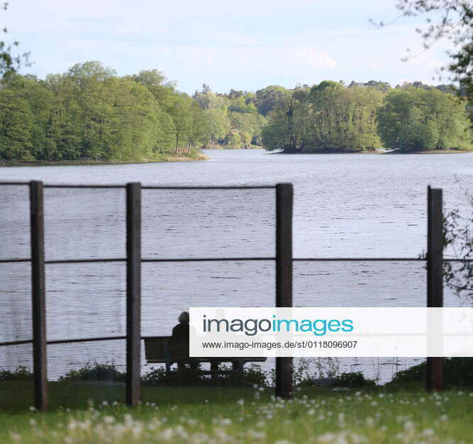 Two people sitting on a bench at the Wall memorial at Groß Glienicker ...