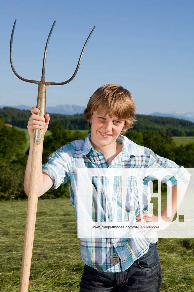 Boy with hayfork on meadow, proud RF, Judith Haeusler