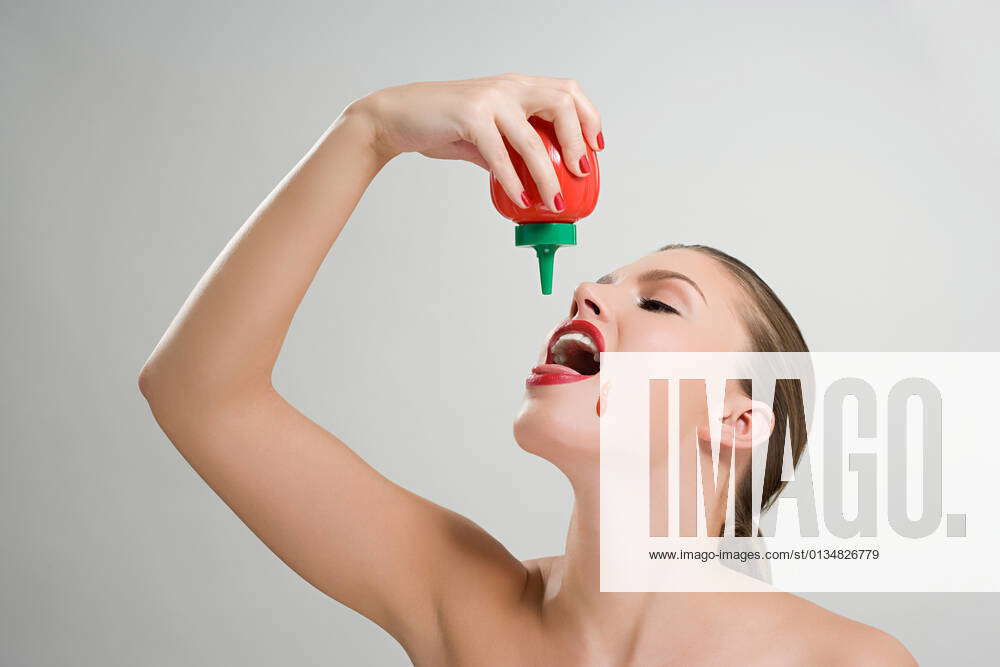 Woman pouring tomato ketchup into her mouth