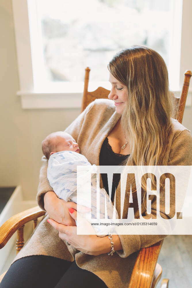 Mother sitting in rocking chair holding newborn baby boy