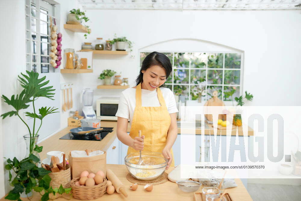 Female mixing flour with eggs while using whisk. She is cooking bakery ...