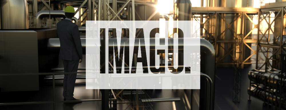 Technician supervisor looking out onto an oil refinery at sunset with ...