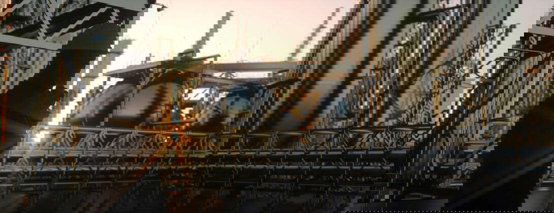 Technician supervisor looking out onto an oil refinery at sunset with ...