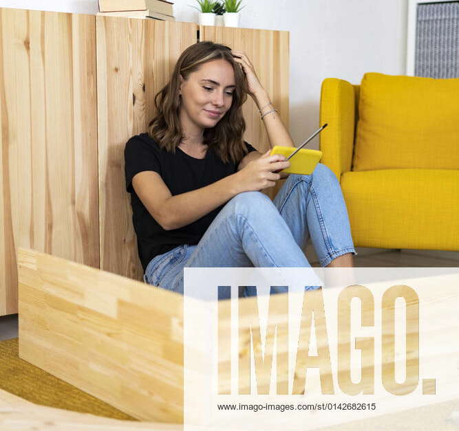 Smiling Young Woman With Screwdriver Using Mobile Phone In Living Room