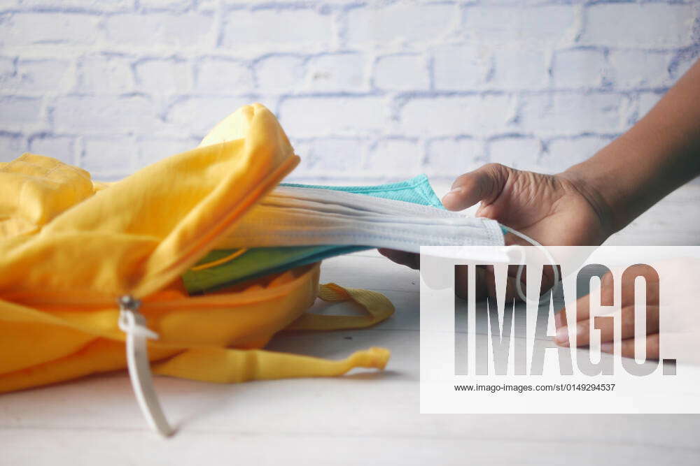 Putting hand sanitizer and face mask in a school bag Student school bag ...