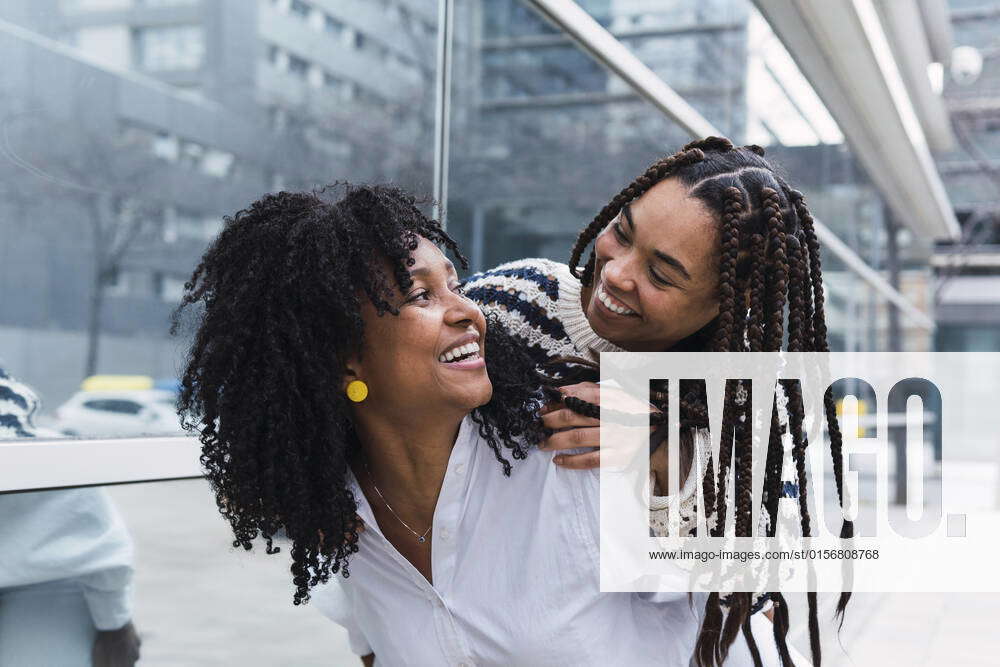 Cheerful businesswoman giving piggyback ride to colleague at office ...