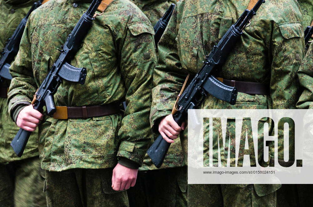 Soldiers in camouflage stand in formation with weapons body only ...