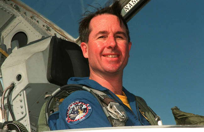 STS-85 Mission Specialist Stephen K. Robinson smiles as he is assisted ...