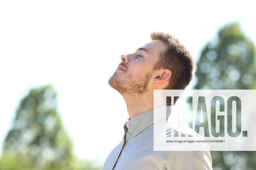 Man breathing fresh air standing outdoors, Side view of a man breathing ...