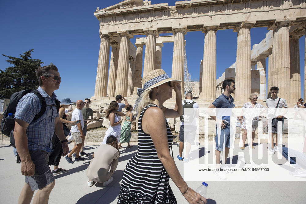 Visitors In Acropolis Of Athens A woman holds her hat in front of the Parthenon because of the