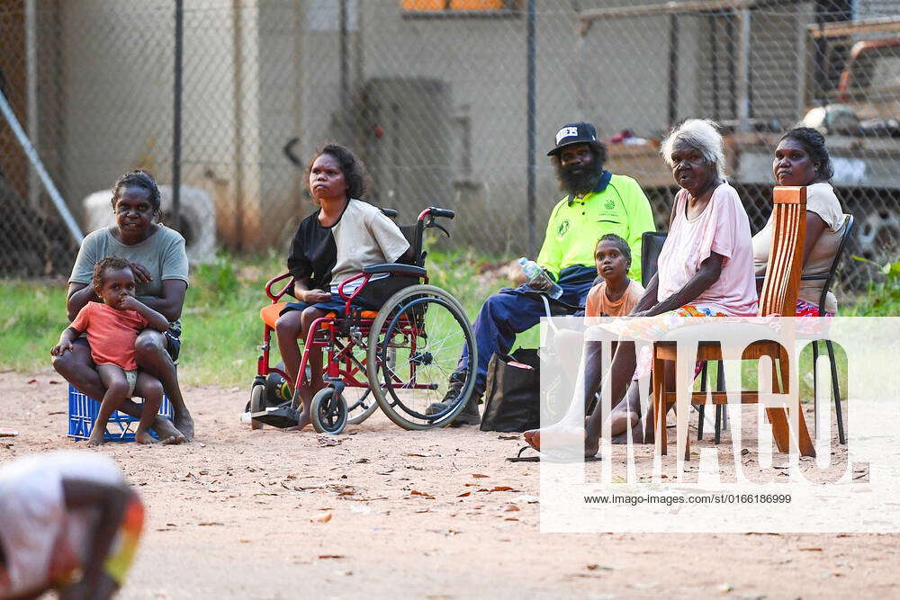 AURUKUN FEATURE, Locals watch children play stick ball on a street in ...